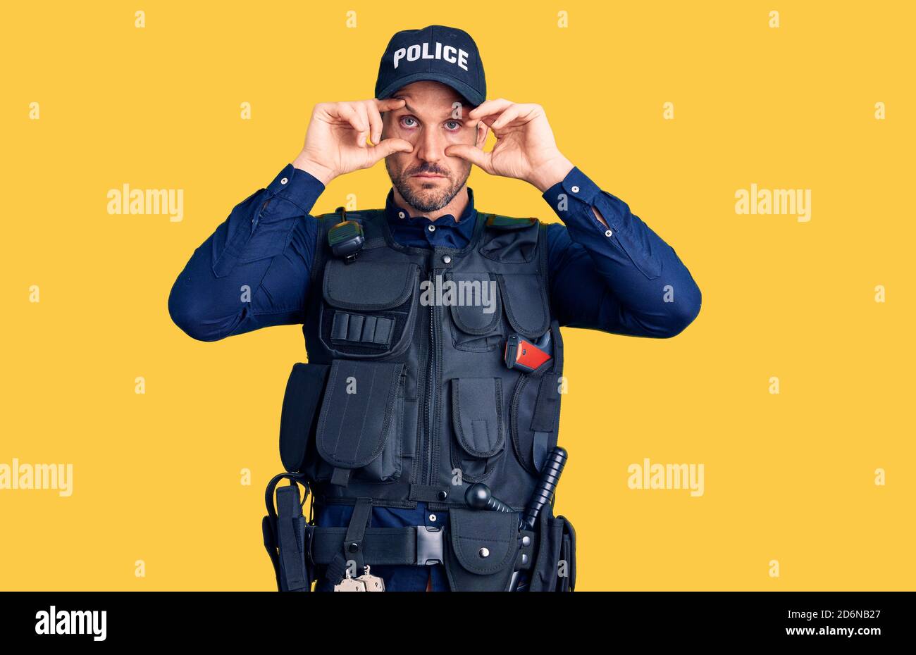 Young handsome man wearing police uniform trying to open eyes with ...