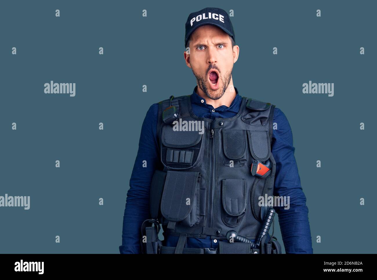 Young handsome man wearing police uniform in shock face, looking ...