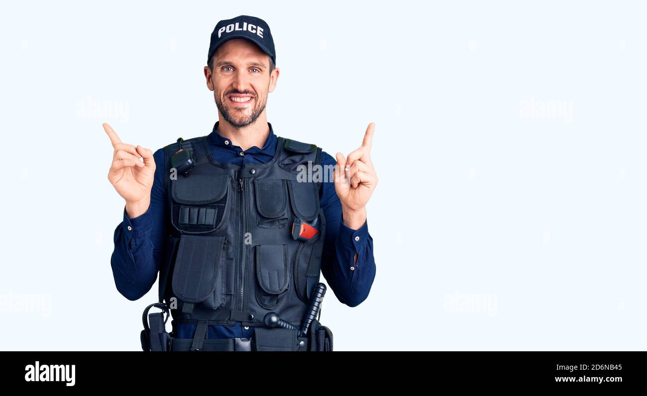 Young handsome man wearing police uniform smiling confident pointing ...