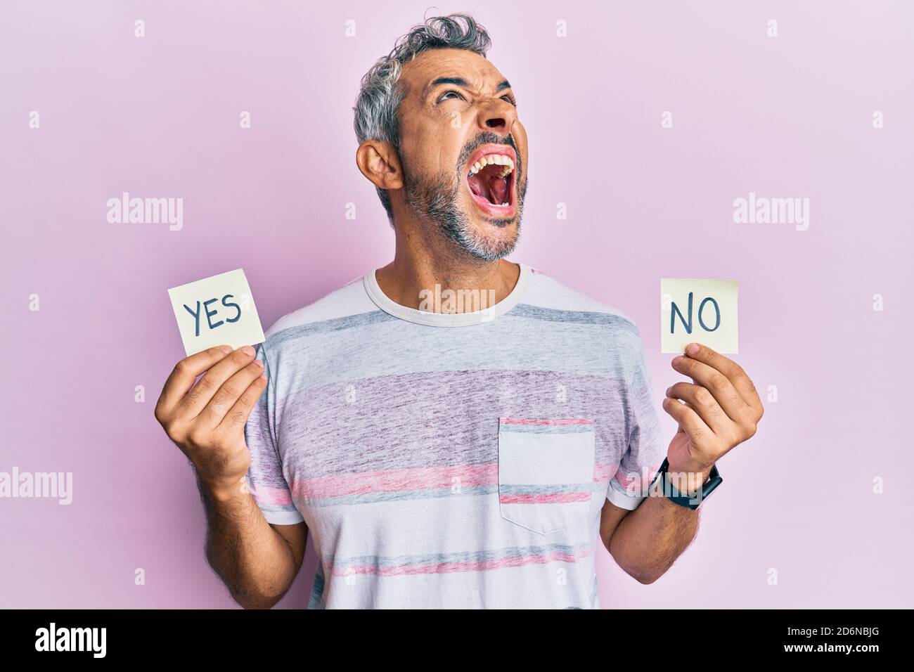 Middle age grey-haired man holding yes and no reminder angry and mad ...