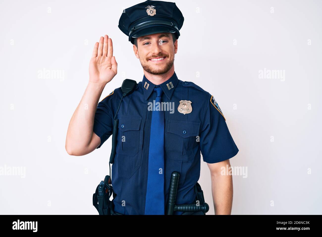 Young caucasian man wearing police uniform waiving saying hello happy ...