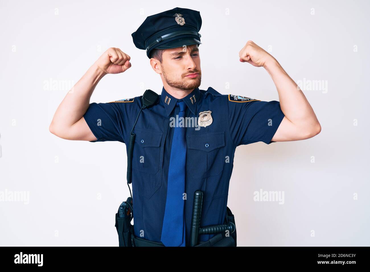 Young caucasian man wearing police uniform showing arms muscles smiling ...