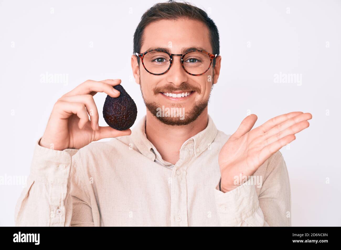 Young handsome man holding avocado celebrating achievement with happy ...