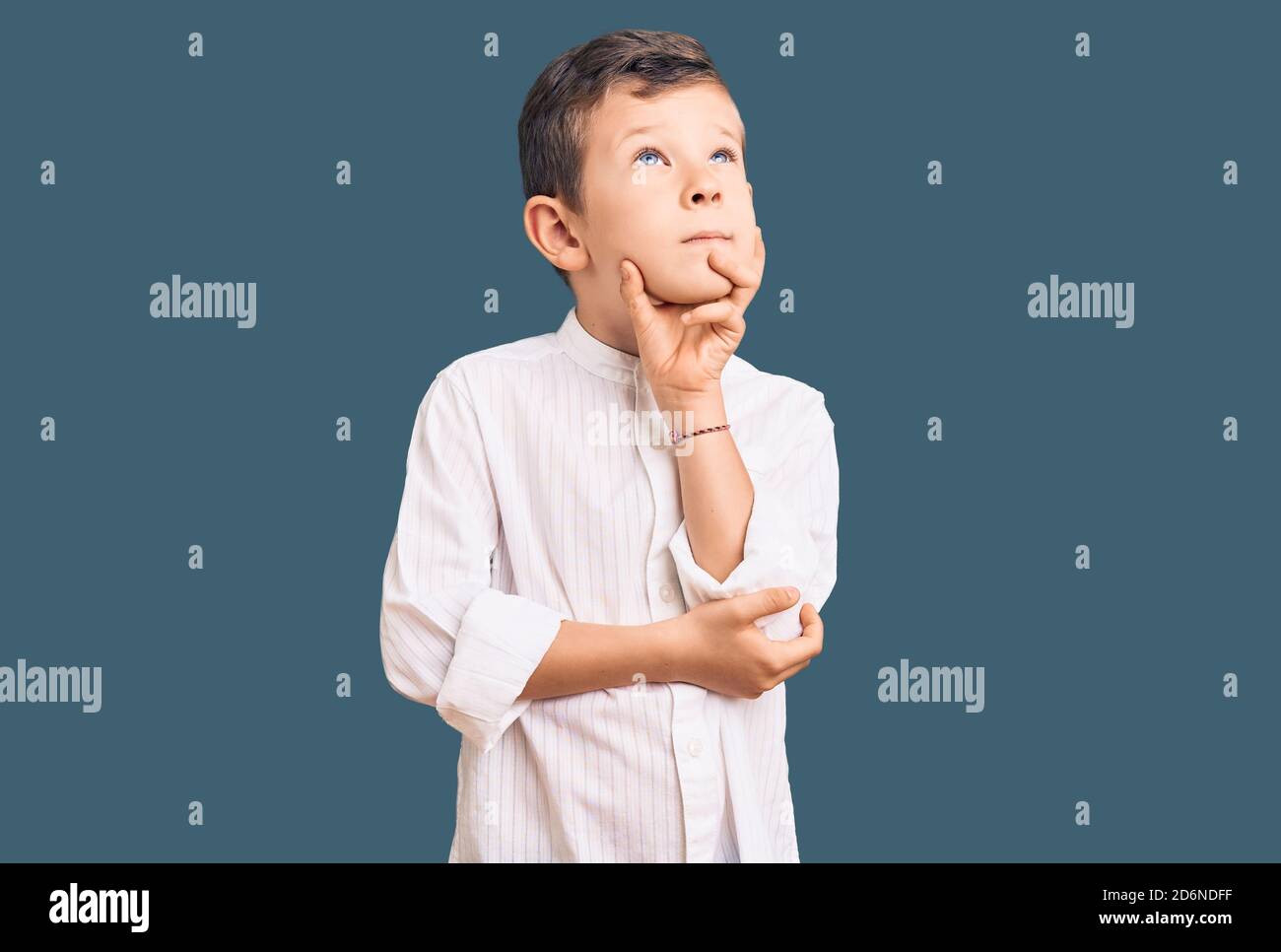 Cute blond kid wearing elegant shirt with hand on chin thinking about ...
