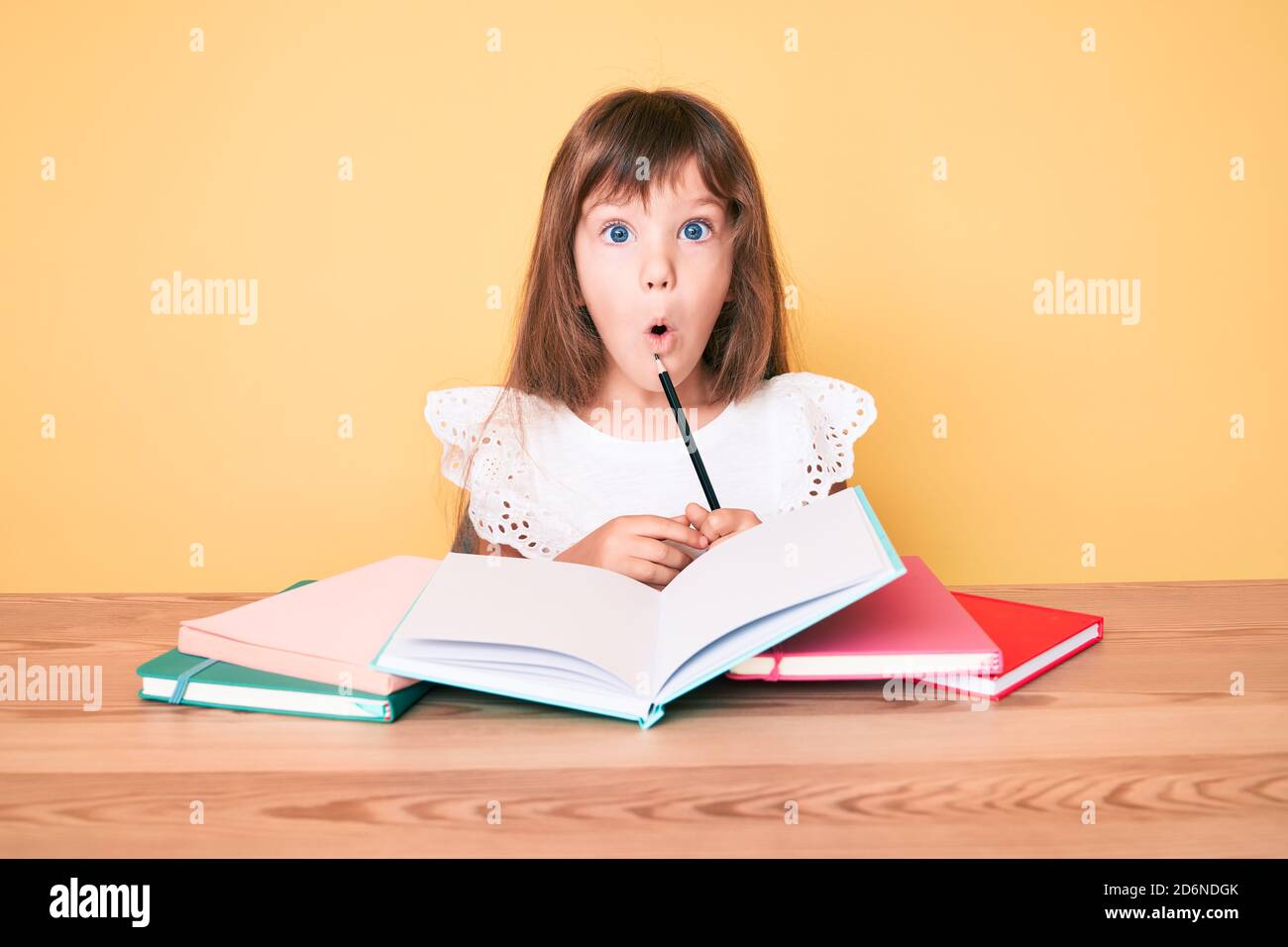 Little caucasian kid girl with long hair studying for school exam ...