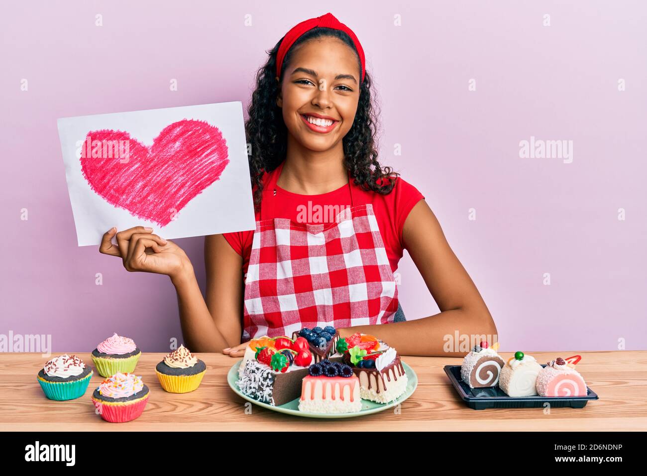 Young african american girl wearing baker uniform holding heart draw ...
