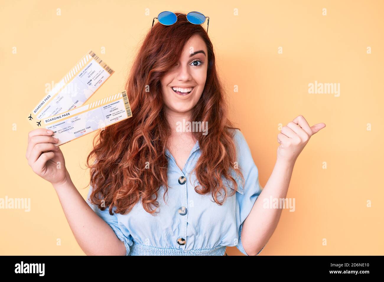 Young beautiful woman holding boarding pass pointing thumb up to the ...