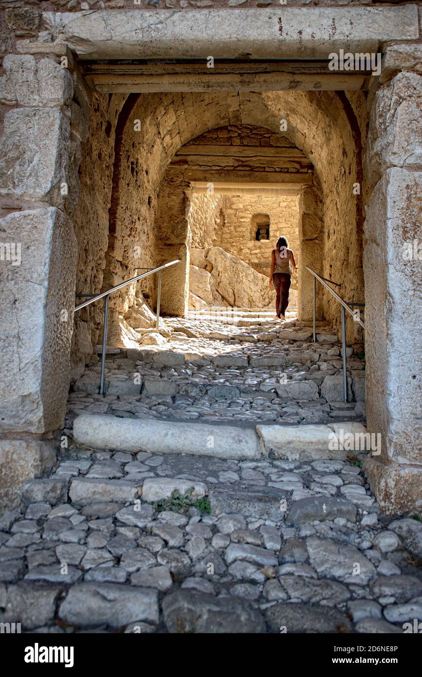 ACROCORINTH, GREECE - JULY 12, 2009: woman crosses stone entrance ...