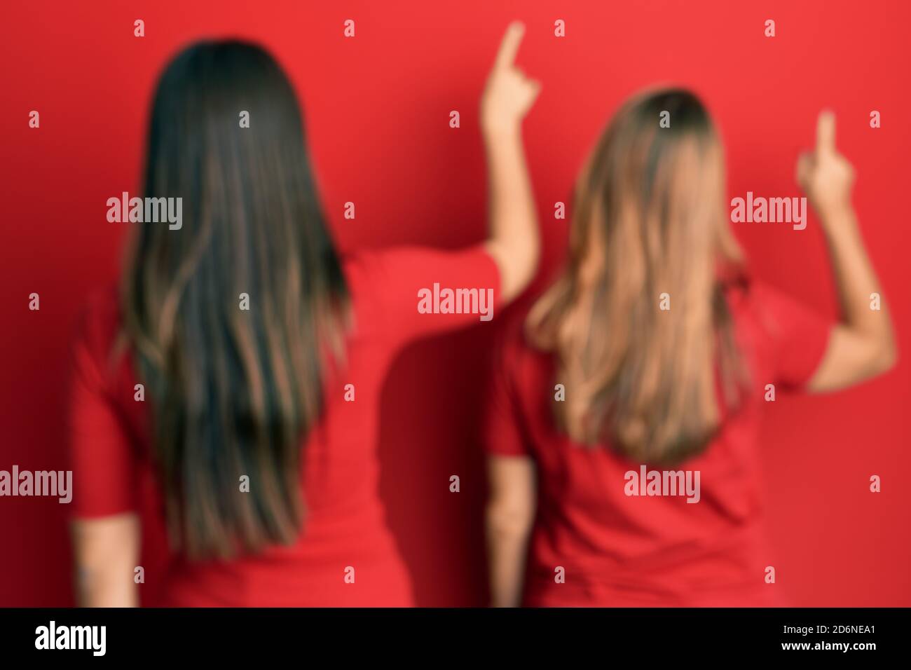 Hispanic family of mother and daughter wearing casual clothes over red ...