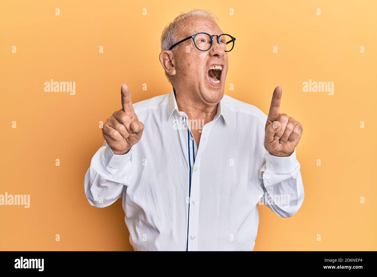 Senior caucasian man pointing up with fingers angry and mad screaming ...
