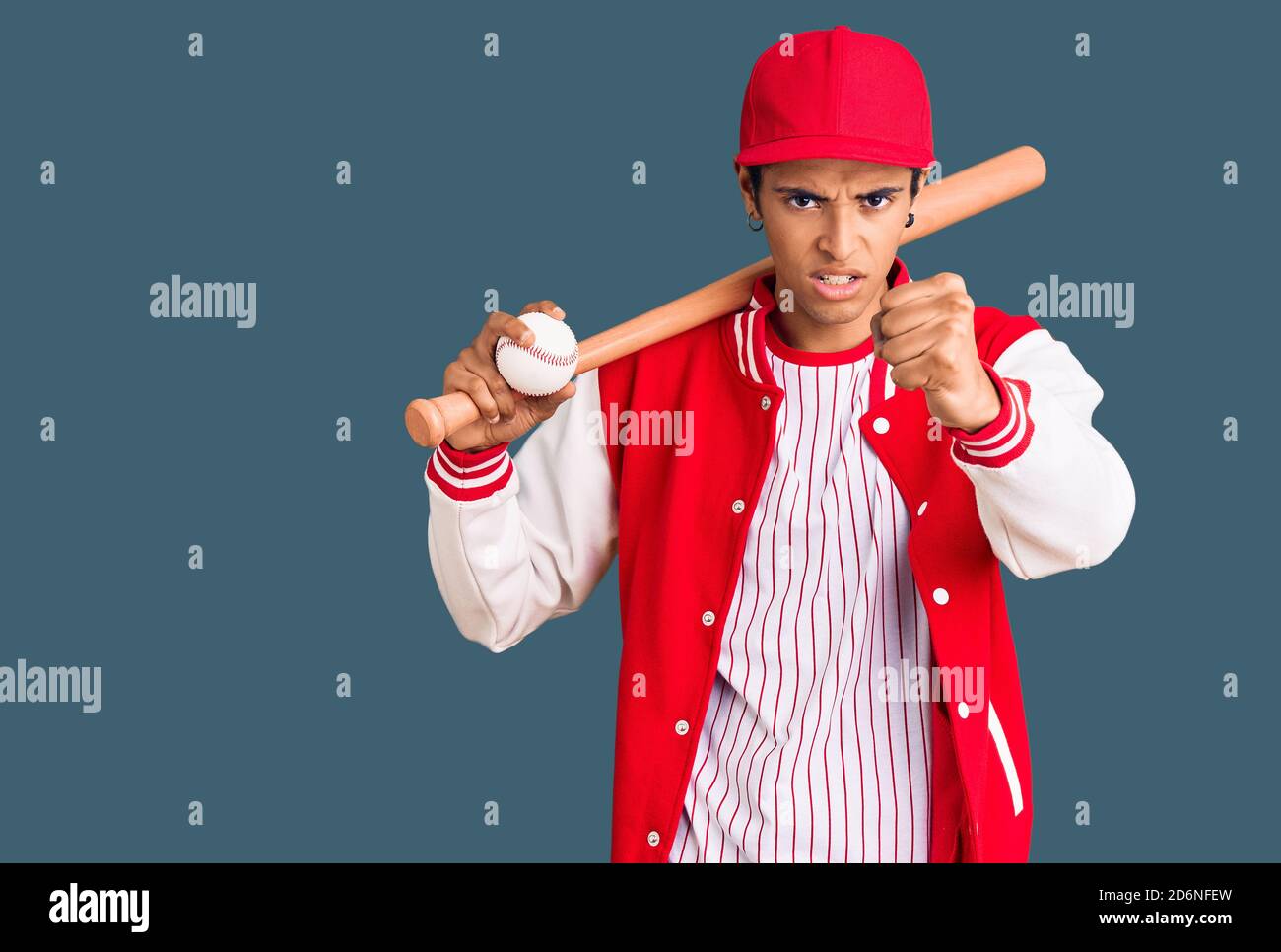 Young african amercian man playing baseball holding bat and ball ...
