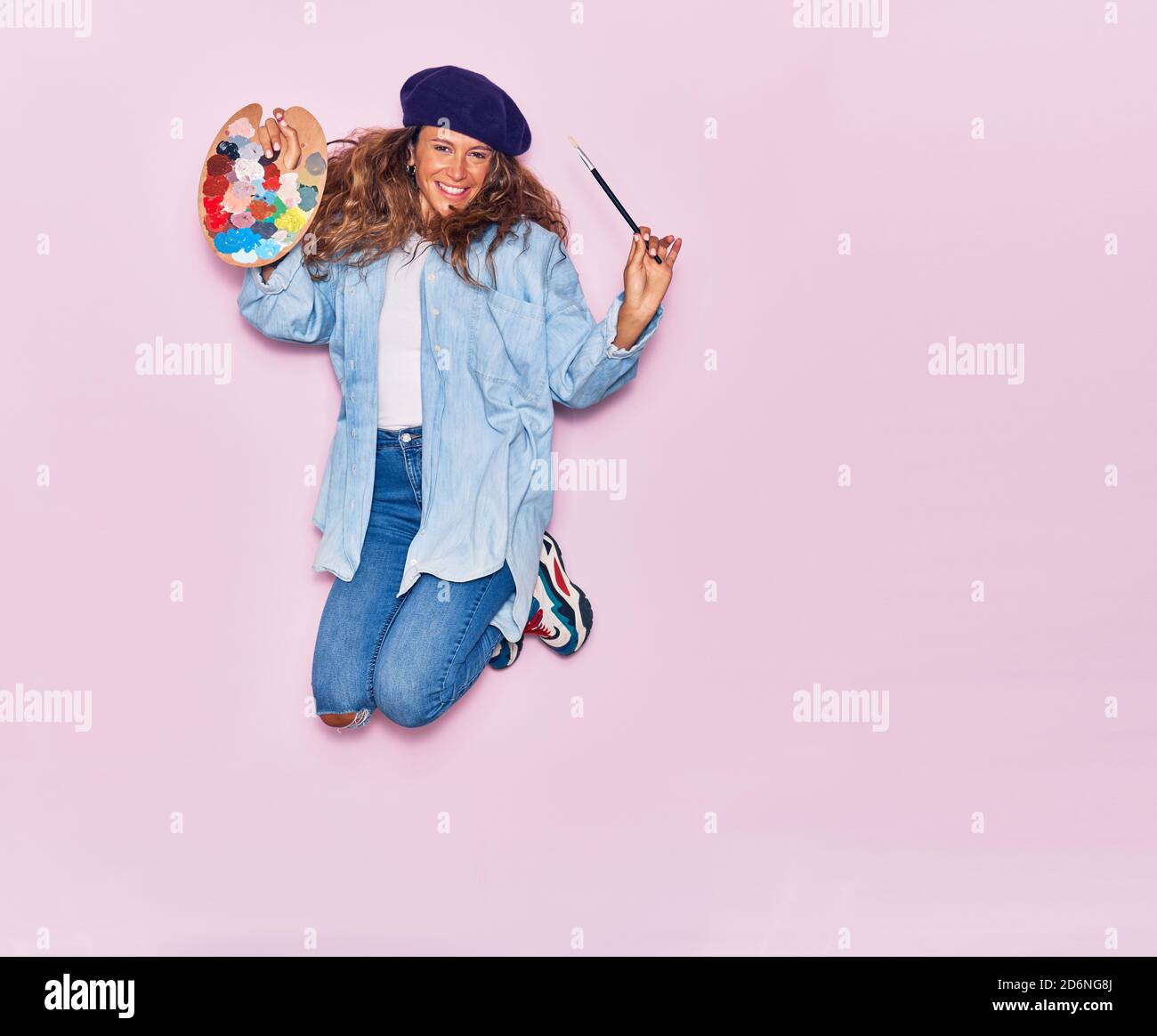 Young beautiful curly artist woman with tattoo wearing french beret ...