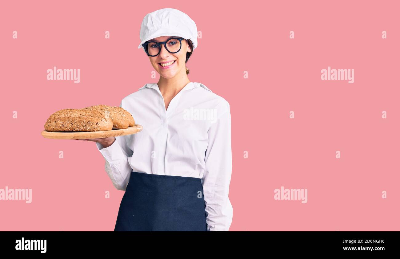Beautiful brunette young woman wearing baker uniform holding homemade ...