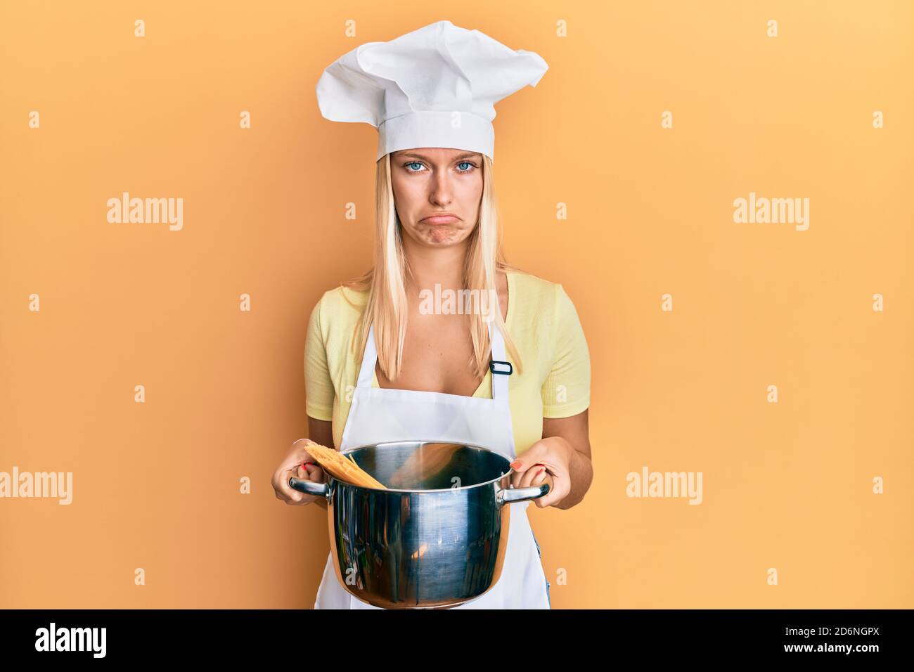 Young blonde girl cooking spaghetti depressed and worry for distress ...