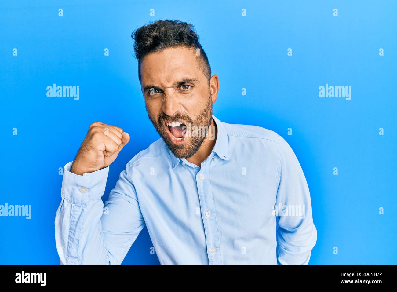 Handsome man with beard wearing casual clothes angry and mad raising ...