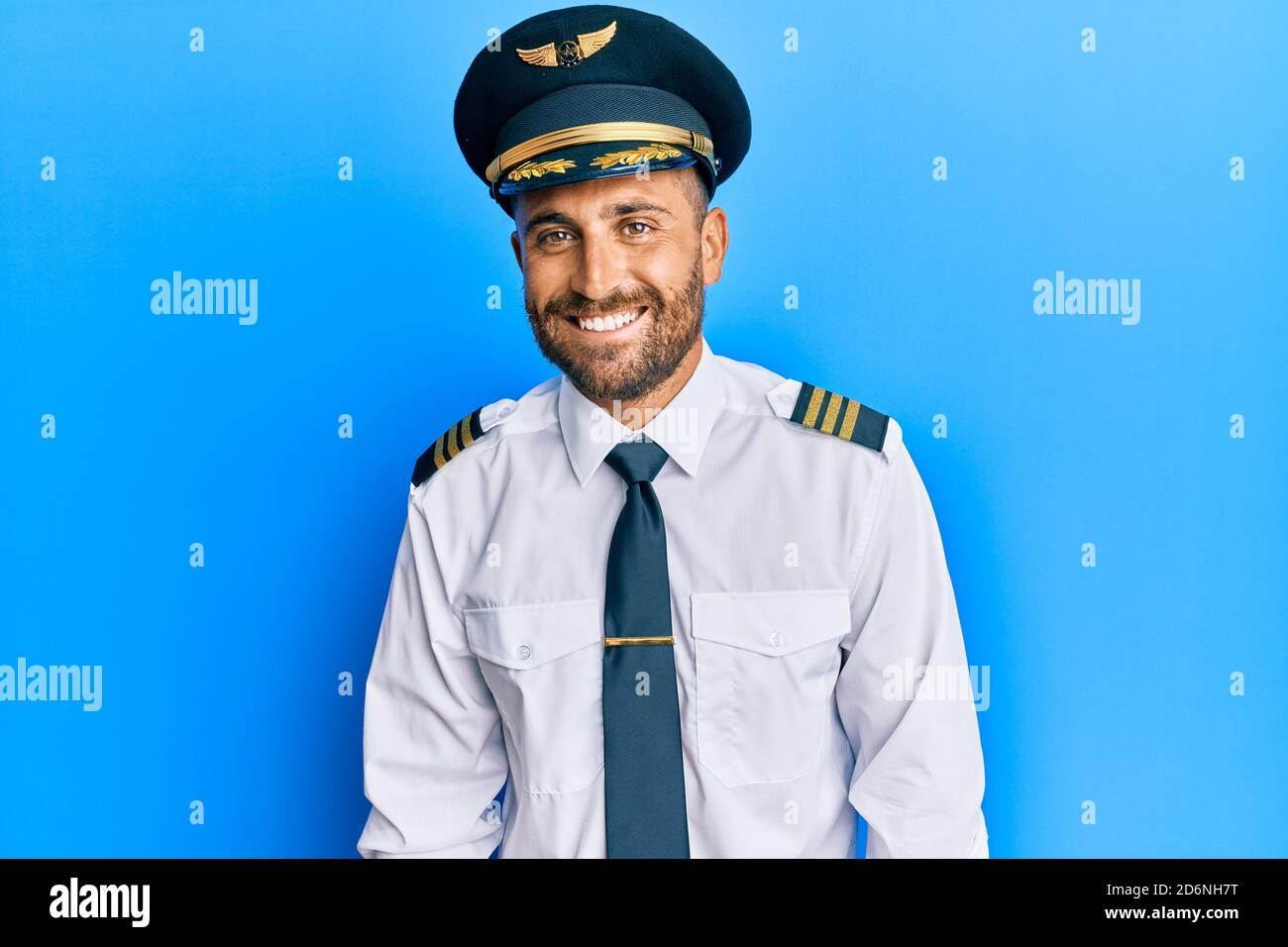 Handsome man with beard wearing airplane pilot uniform with a happy and ...