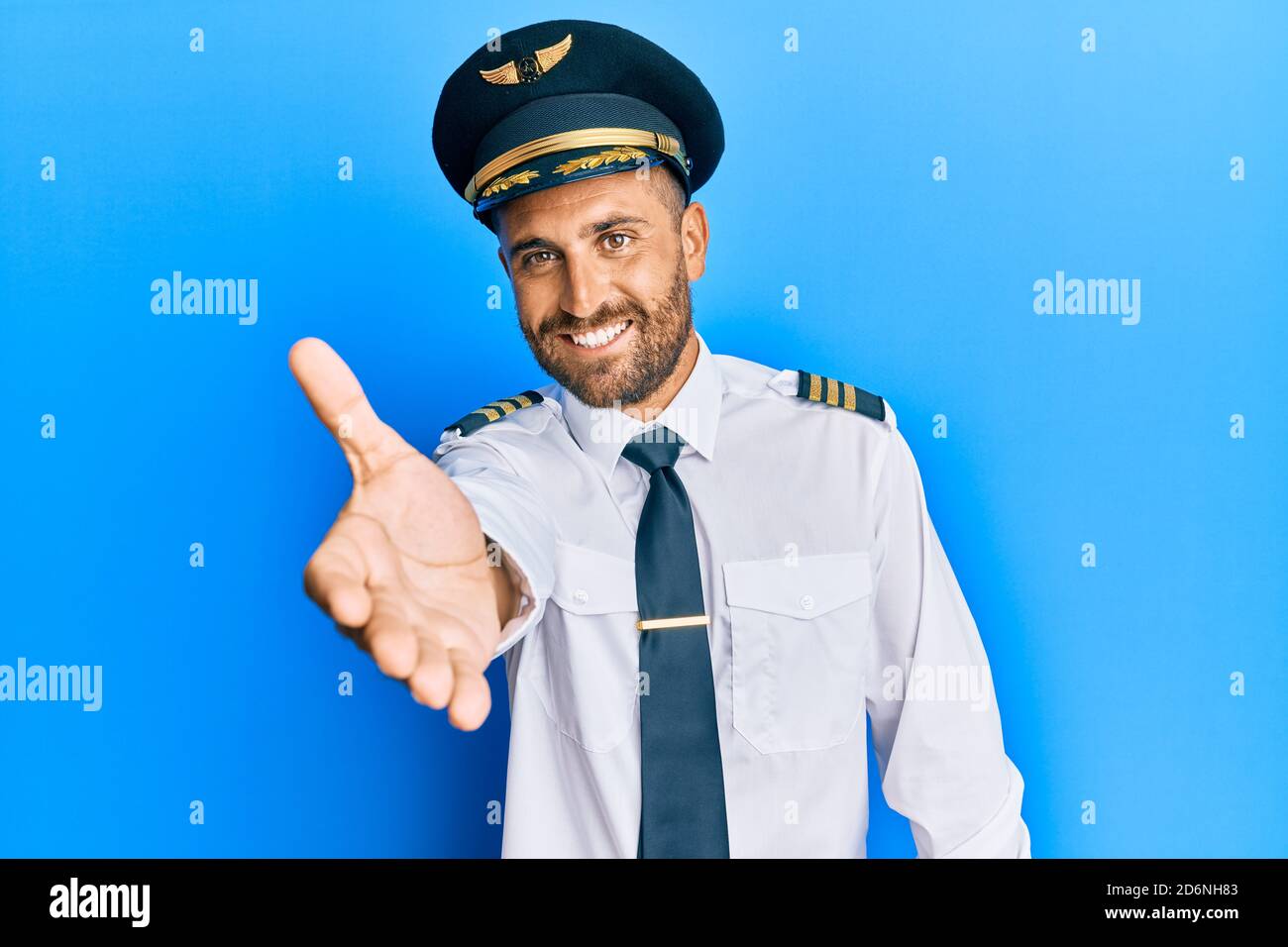 Handsome man with beard wearing airplane pilot uniform smiling friendly ...