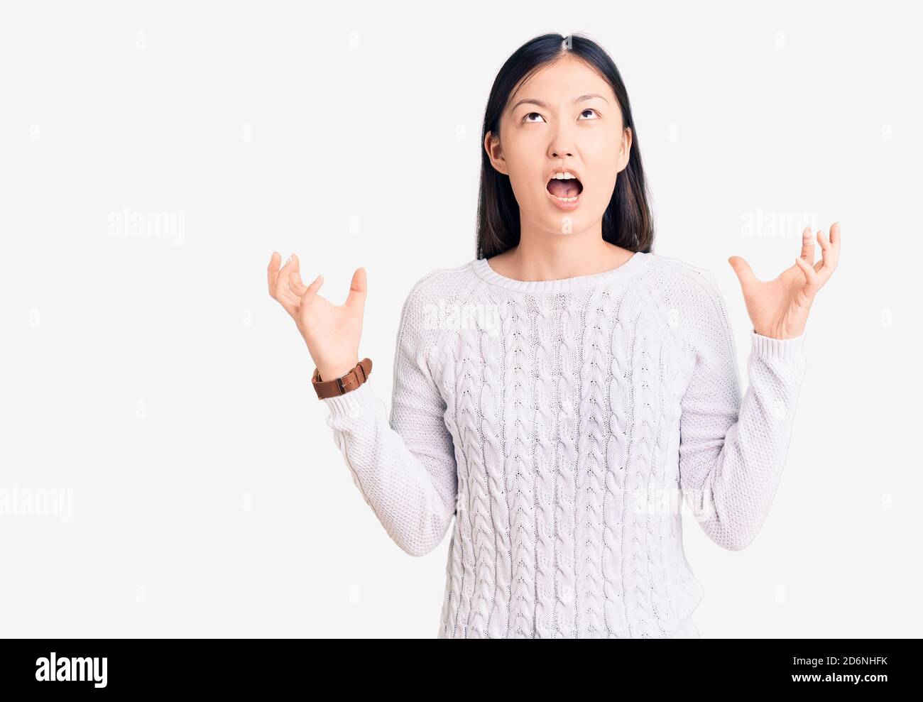 Young beautiful chinese woman wearing casual sweater crazy and mad ...