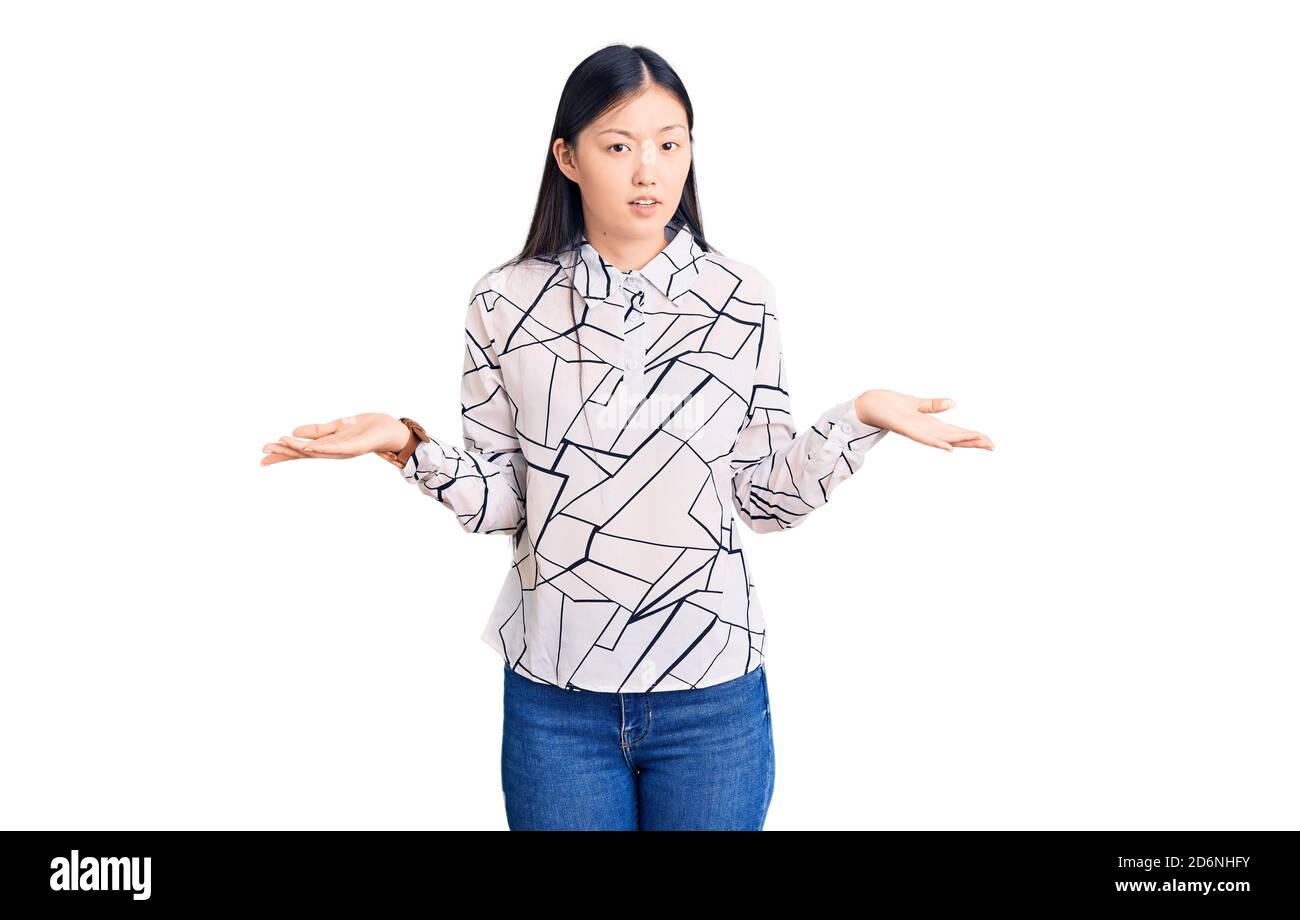 Young beautiful chinese woman wearing casual shirt clueless and ...