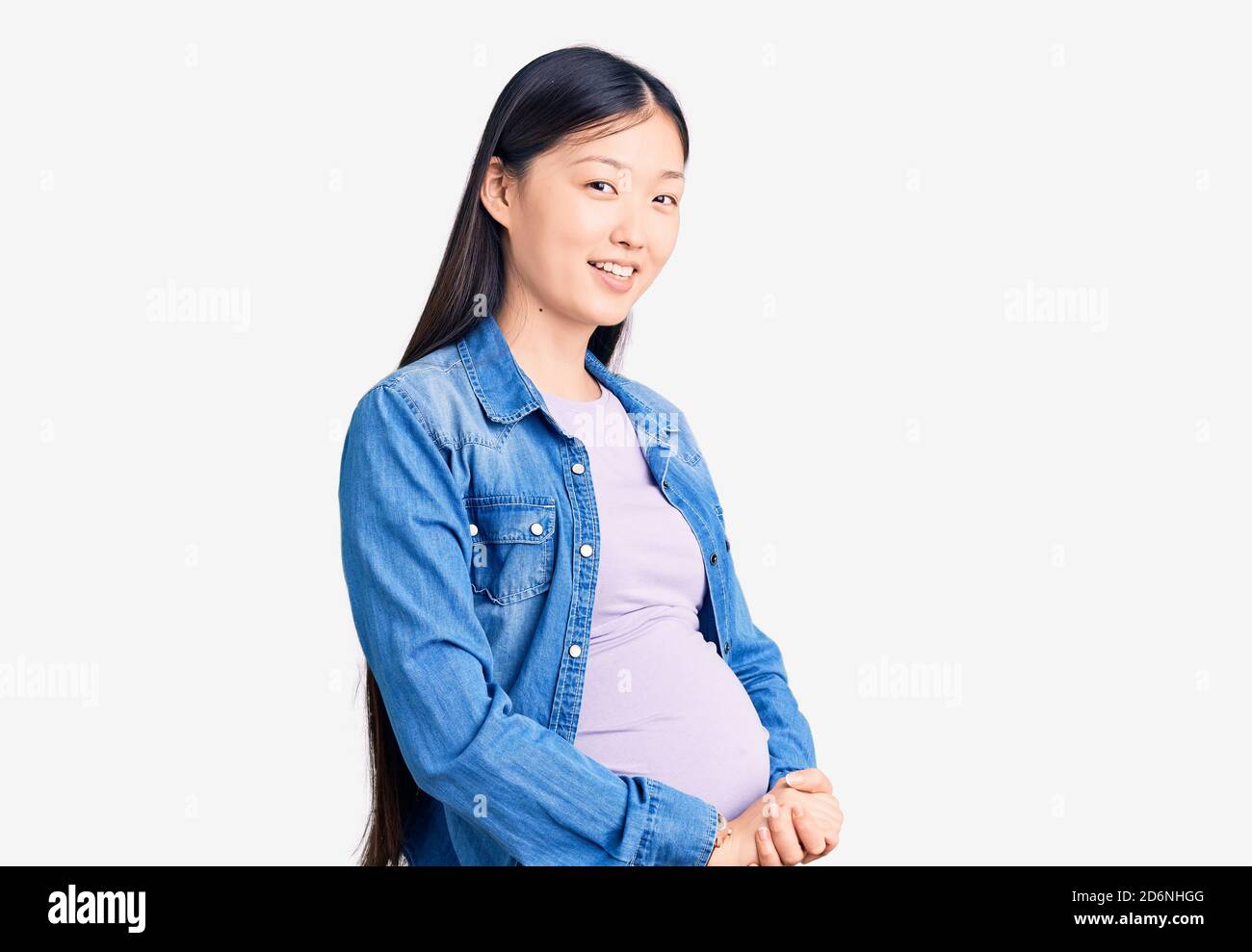 Young beautiful chinese woman pregnant expecting baby with hands ...