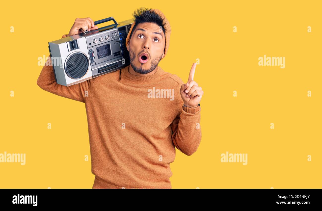 Handsome latin american young man holding boombox, listening to music ...
