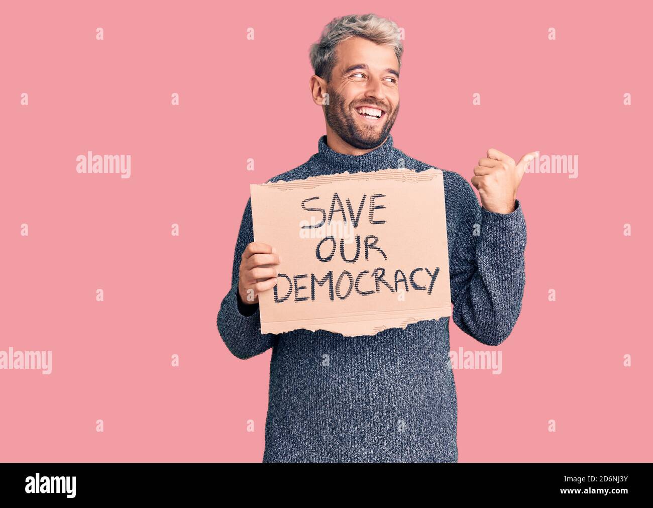 Young blond man holding save our democracy cardboard banner pointing ...