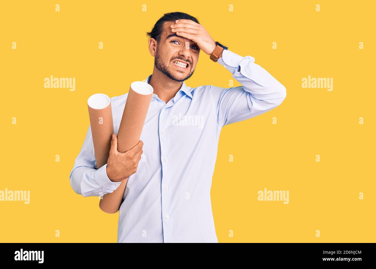 Young handsome man holding paper blueprints stressed and frustrated ...