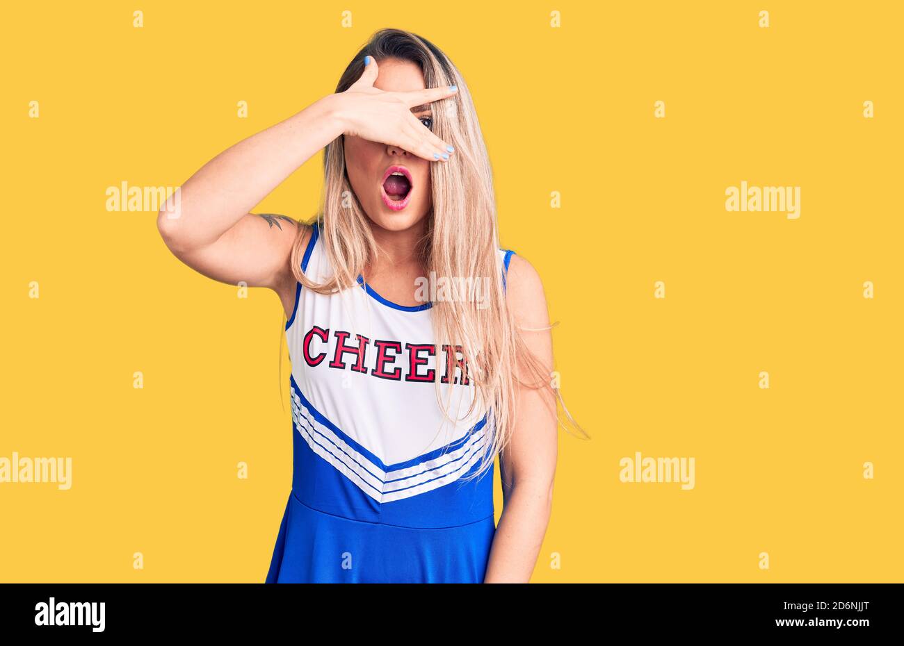 Young Beautiful Blonde Woman Wearing Cheerleader Uniform Peeking In