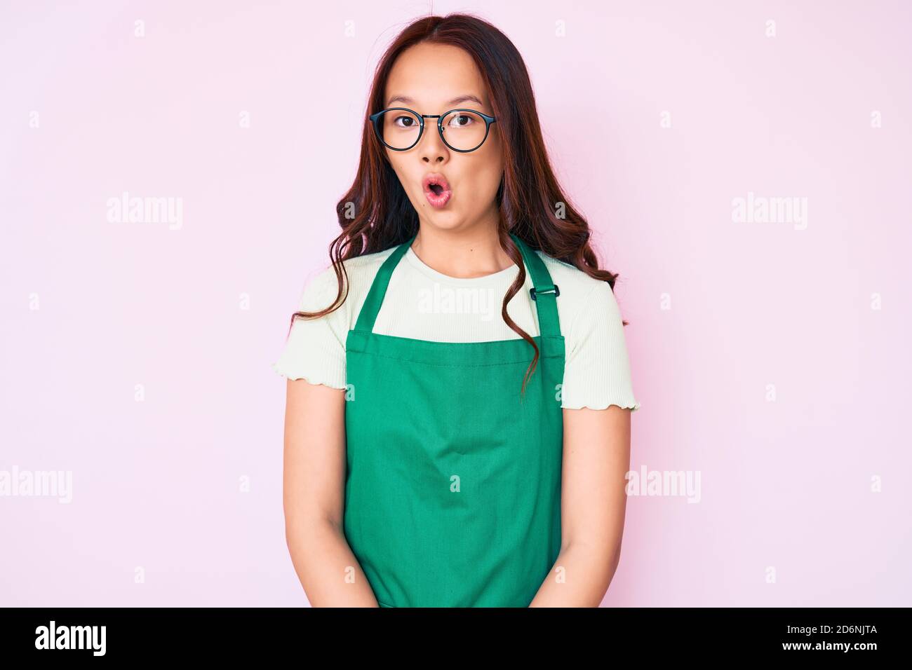 Young beautiful chinese girl wearing cleaner apron afraid and shocked ...