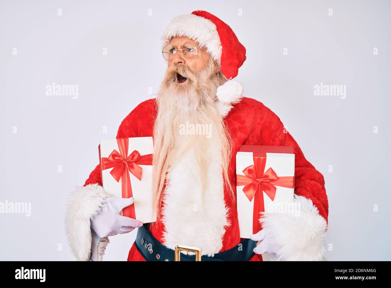 Old senior man wearing santa claus costume holding presents angry and ...