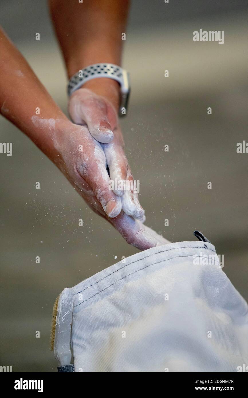 A person applies dry chalk to their hands for better grip before ...