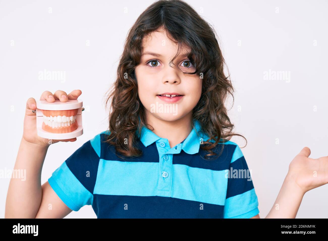 Cute hispanic child with long hair holding denture celebrating ...