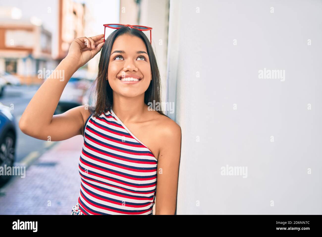 Young latin girl smiling happy leaning on the wall at the city Stock ...