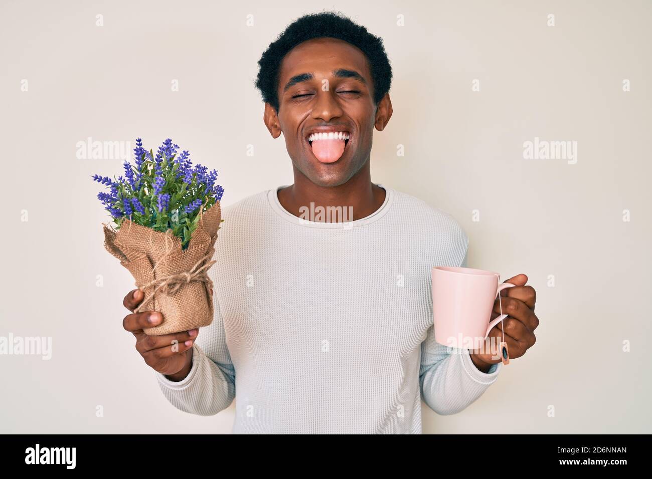 Indian man drinking a cup of infused lavender sticking tongue out happy ...