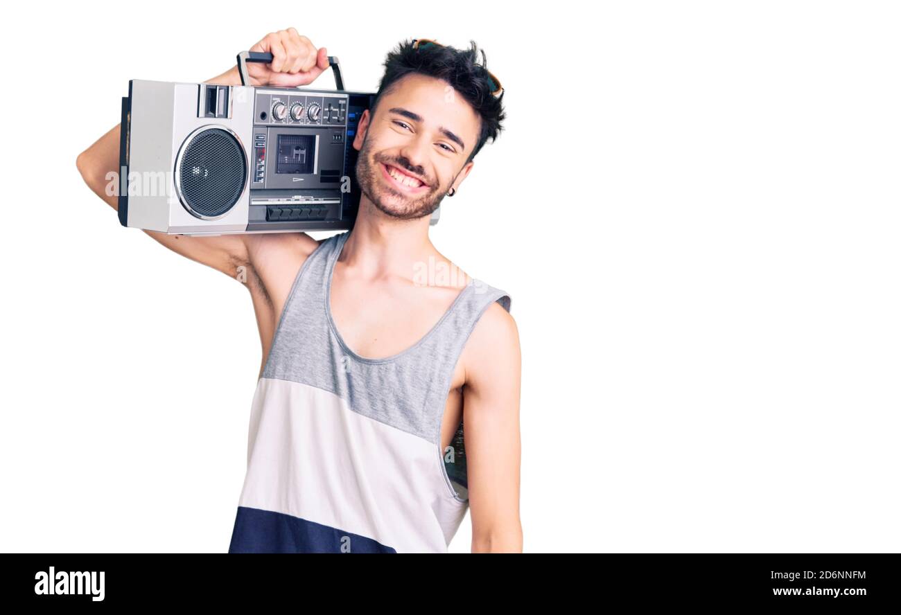 Young hispanic man holding boombox, listening to music looking positive ...