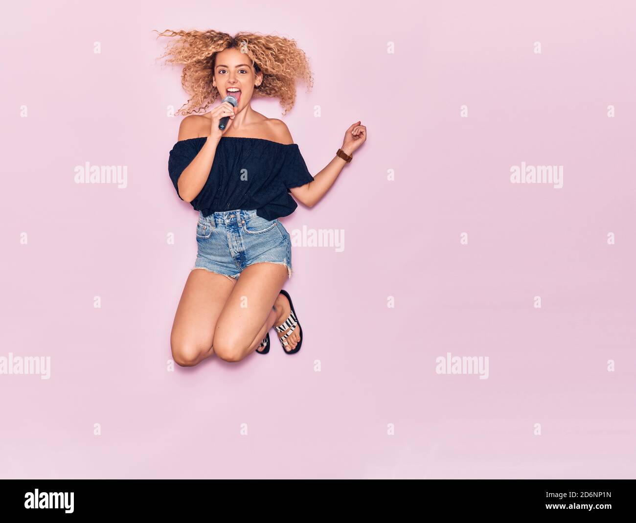 Young beautiful curly singer girl smiling happy singing song using ...