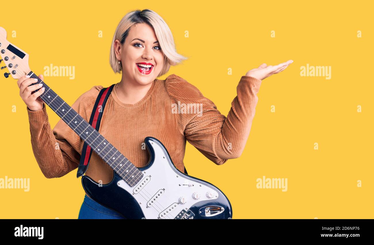 Young blonde plus size woman playing electric guitar celebrating ...