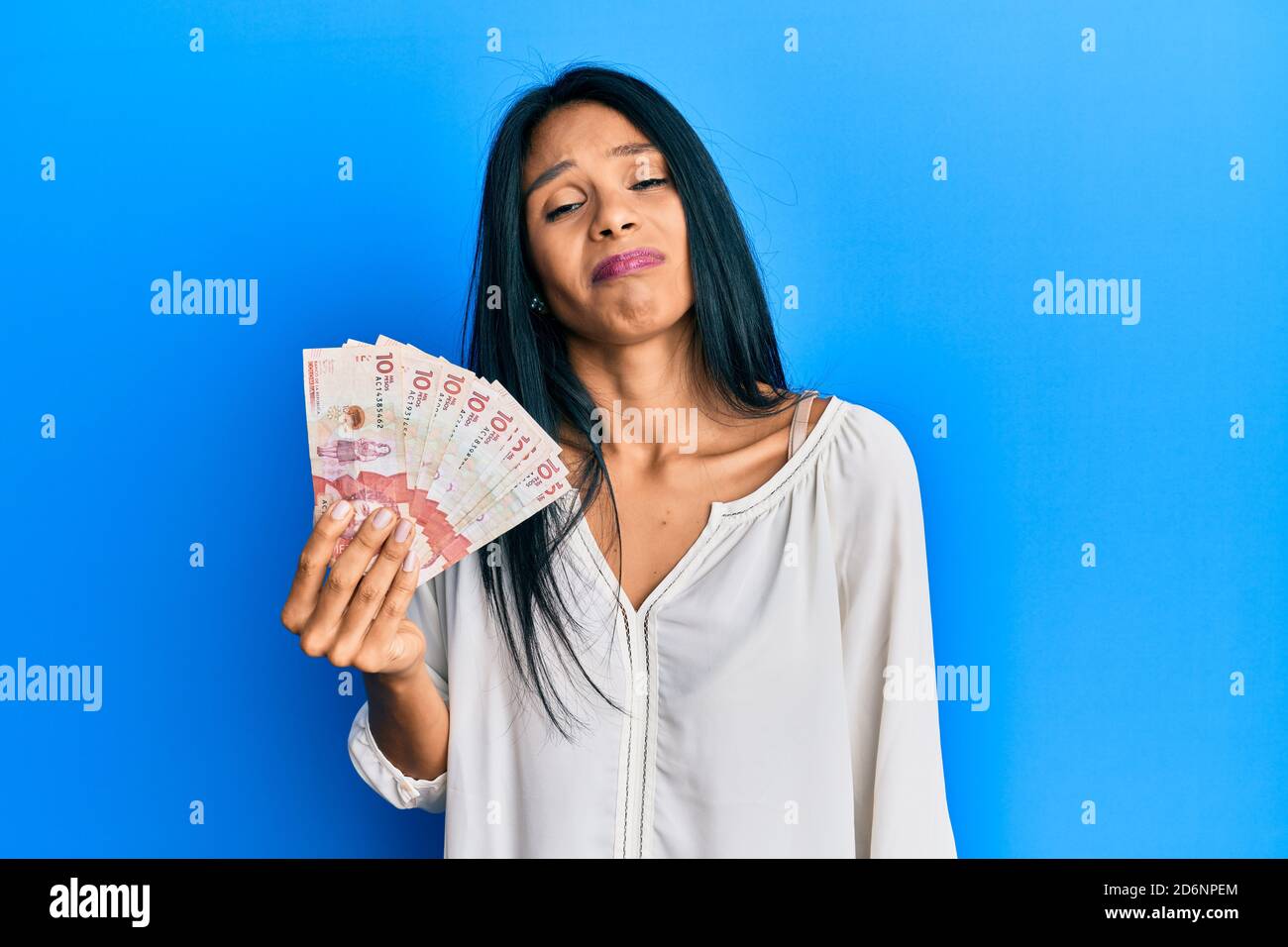 Young african american woman holding 10 colombian pesos banknotes ...