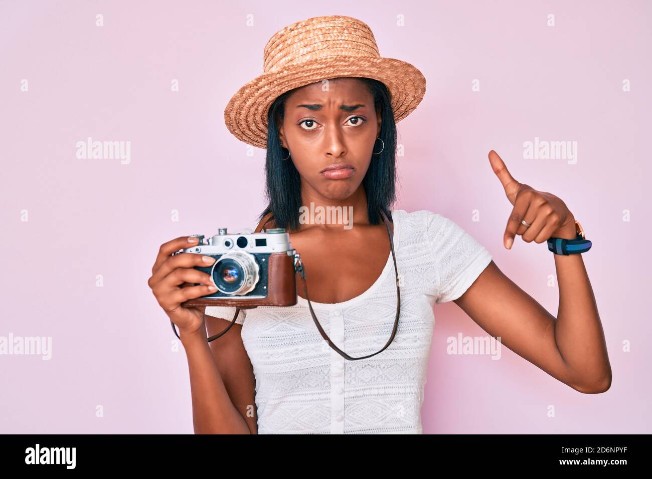 Young african american woman wearing summer hat holding vintage camera ...