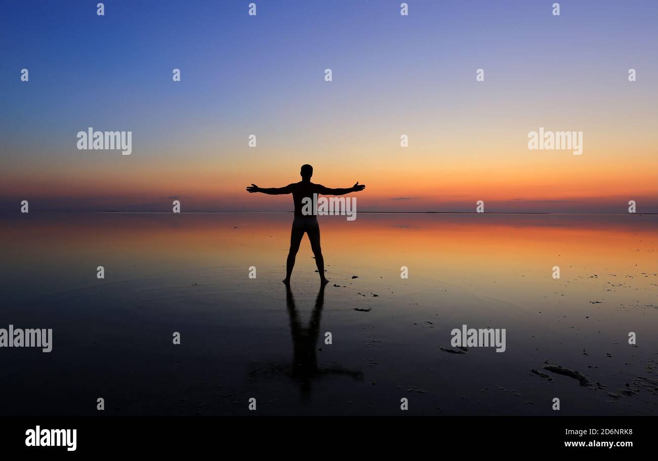 Silhouettes of a man with outstretched arms against the background of ...