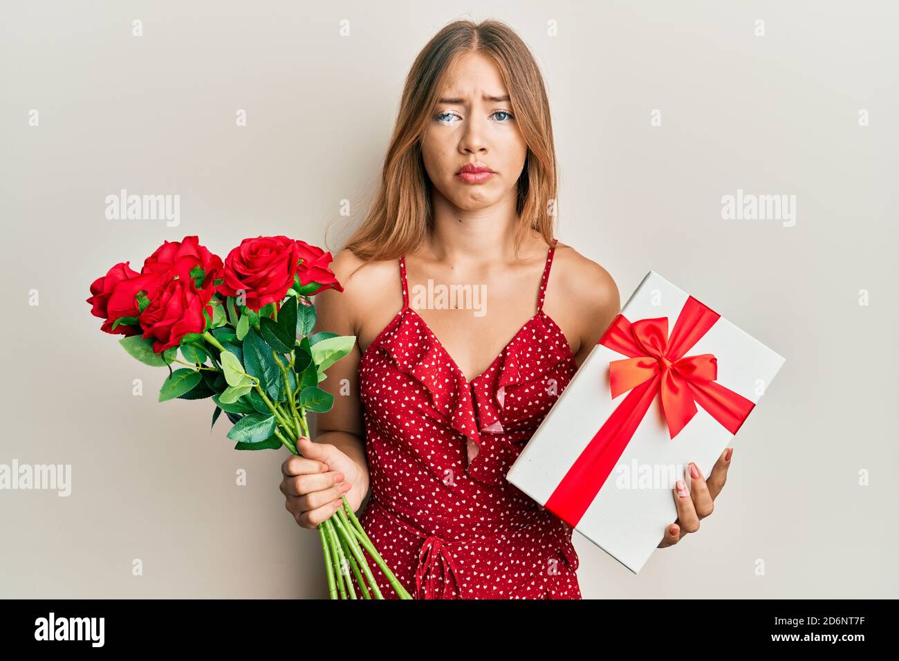 Beautiful young blonde woman holding anniversary present and bouquet of ...