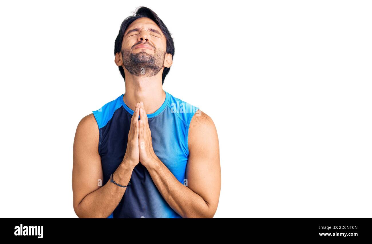 Handsome hispanic man wearing sportswear begging and praying with hands ...