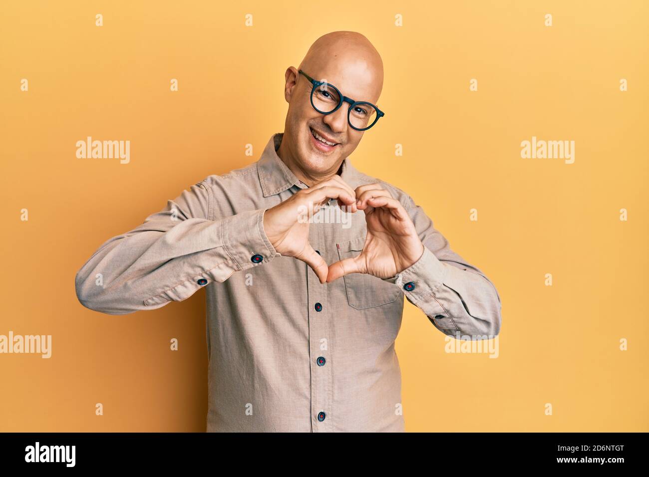 Middle age bald man wearing casual clothes and glasses smiling in love ...