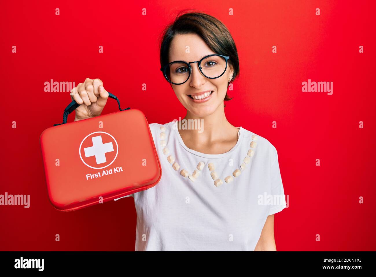 Young brunette woman with short hair holding first aid kit looking ...