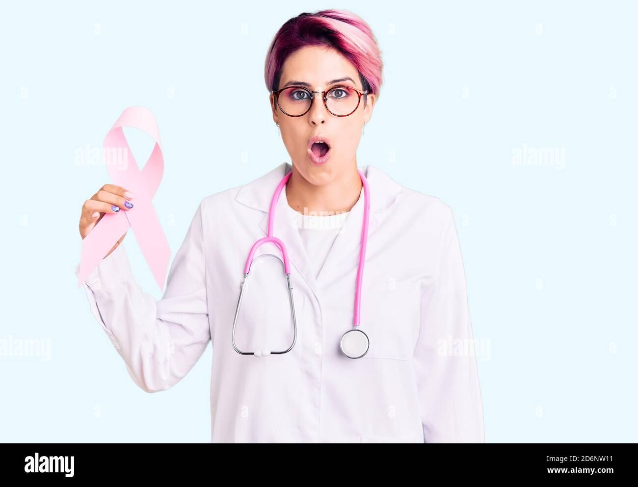 Young beautiful woman with pink hair wearing doctor stethoscope holding ...