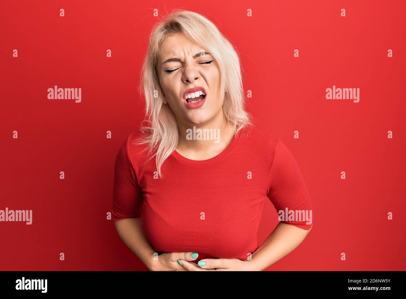 Young blonde girl wearing casual clothes with hand on stomach because ...