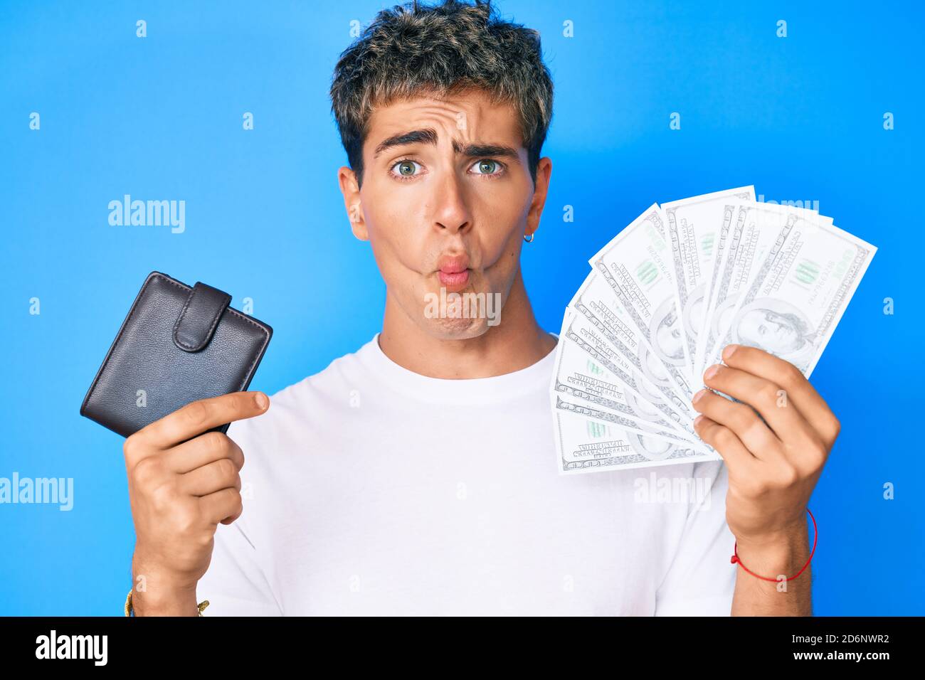 Young handsome man holding wallet and dollars banknotes making fish ...