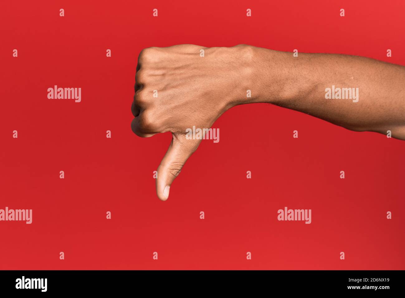 Hand of hispanic man over red isolated background doing thumbs down ...