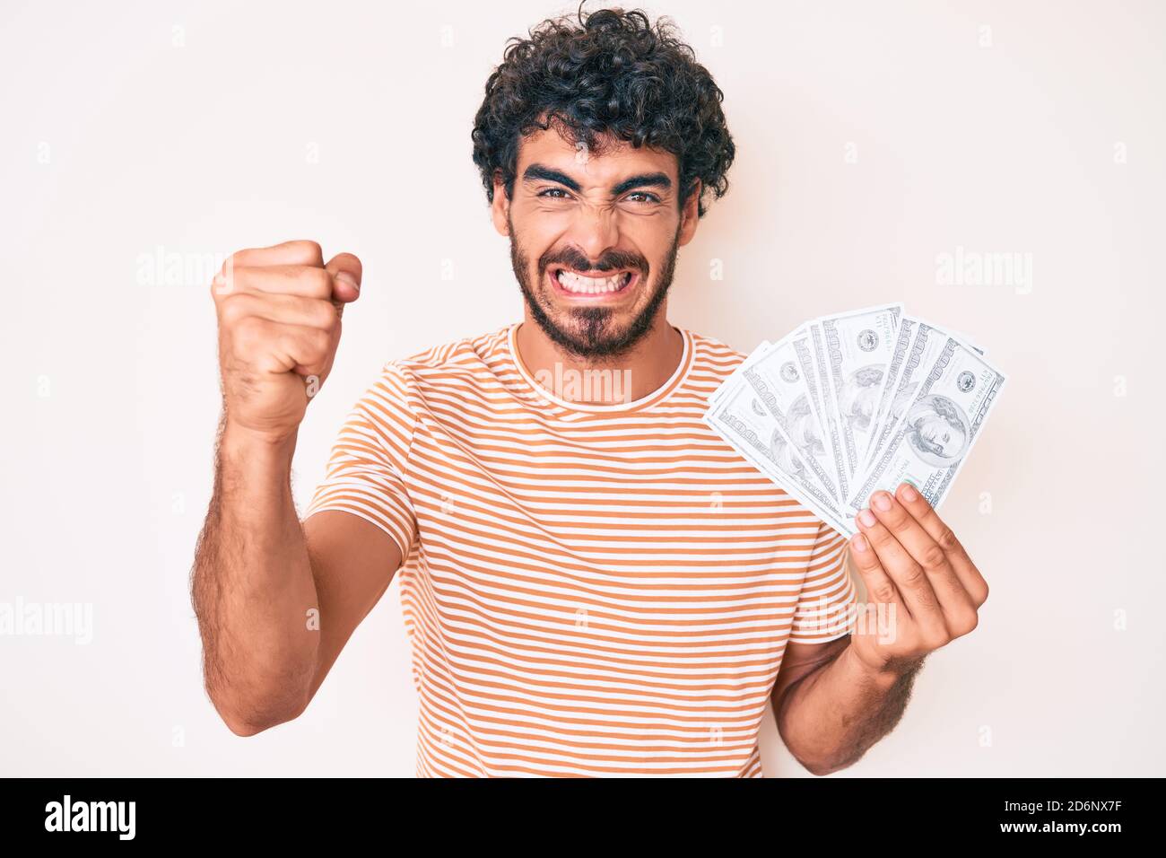 Handsome young man with curly hair and bear holding money bag with ...