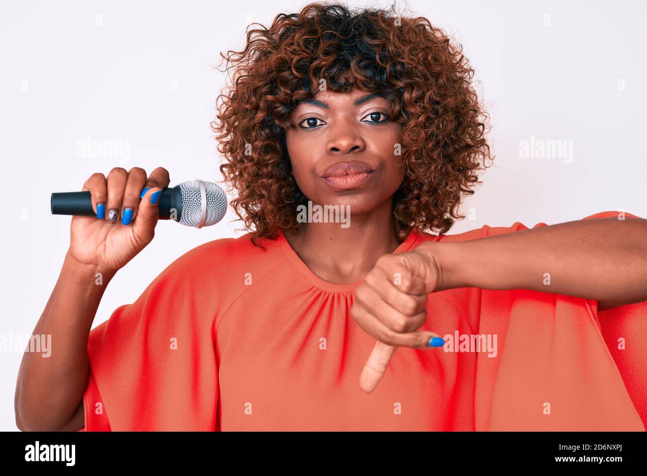 Young african american woman singing song using microphone with angry ...